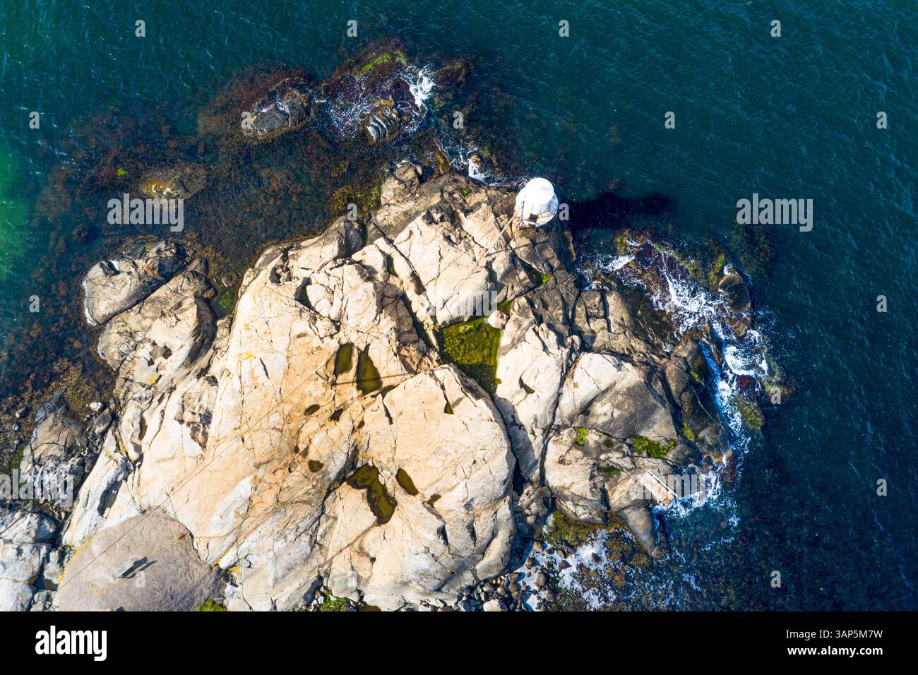 Aerial view of a lighthouse on the rocks with breaking waves, island of ...