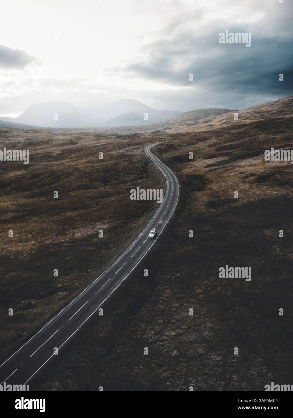 Aerial view of a car cruising through the Scottish highlands near ...