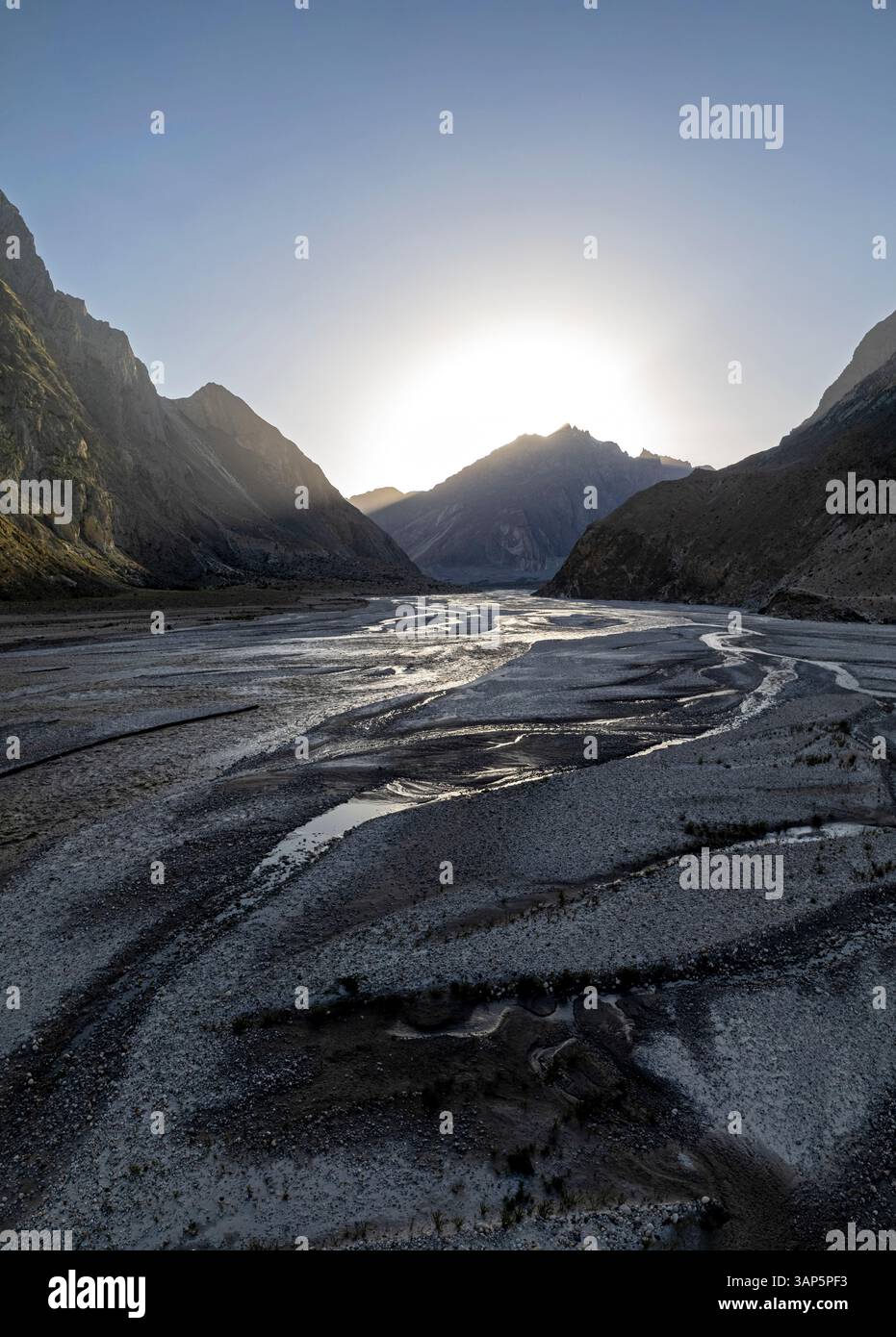 Aerial view of majestic mountains and a serene riverbed at sunrise ...