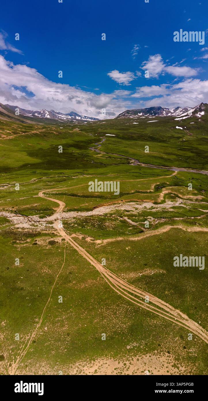 Aerial view of majestic mountains and a winding pathway in a serene ...