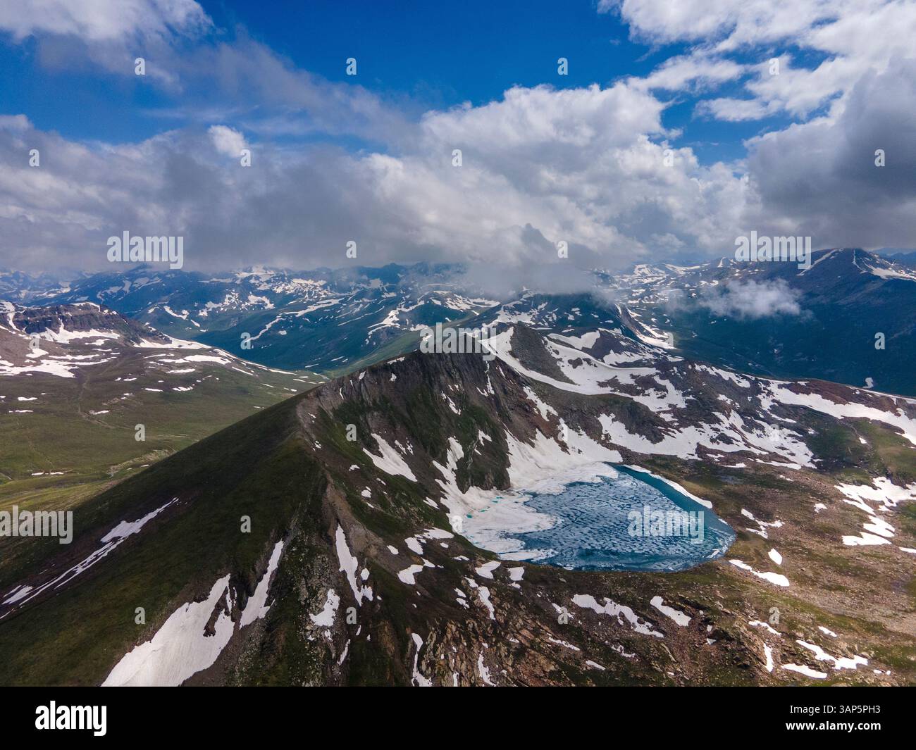 Aerial view of majestic snowy mountains under a blue sky with clouds ...