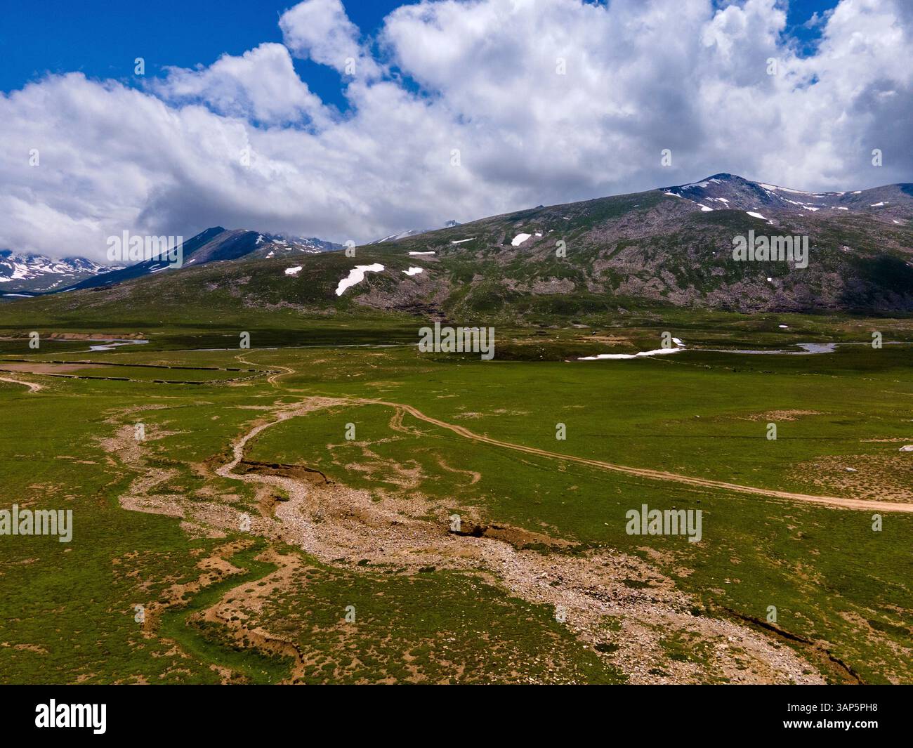 Aerial view of majestic mountains and serene grassland under a vast sky ...