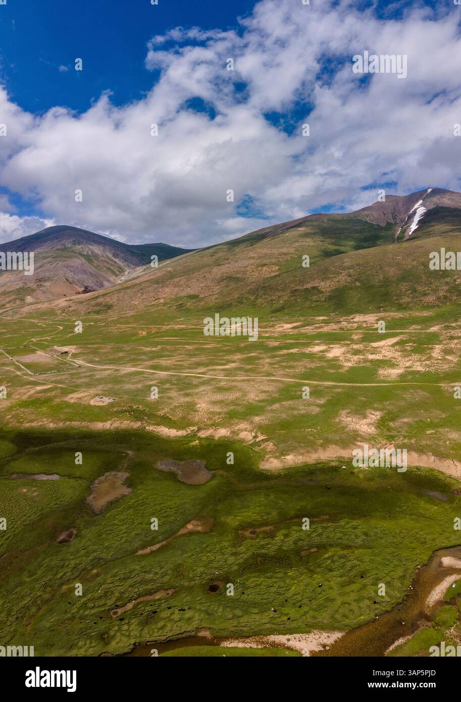 Aerial view of majestic mountains and serene grassland under a ...