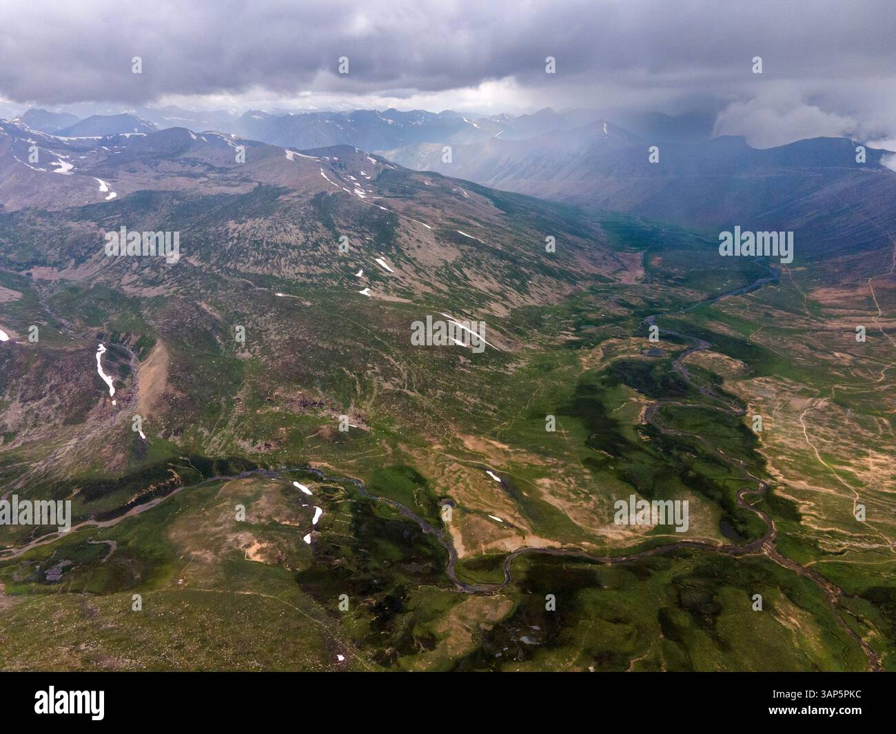 Aerial view of rugged mountains and a serene valley under dramatic ...