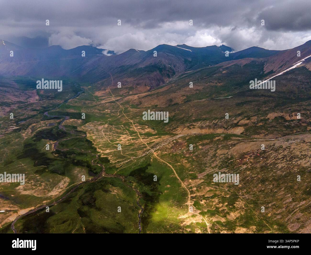 Aerial view of majestic mountains and a serene valley under a dramatic ...