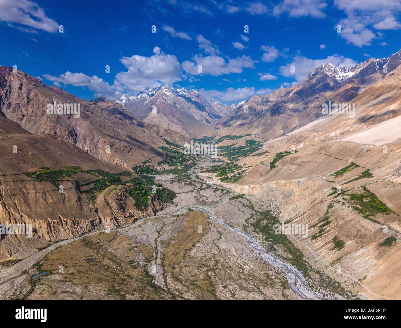 Aerial view of majestic snow-capped mountains and a serene valley in ...