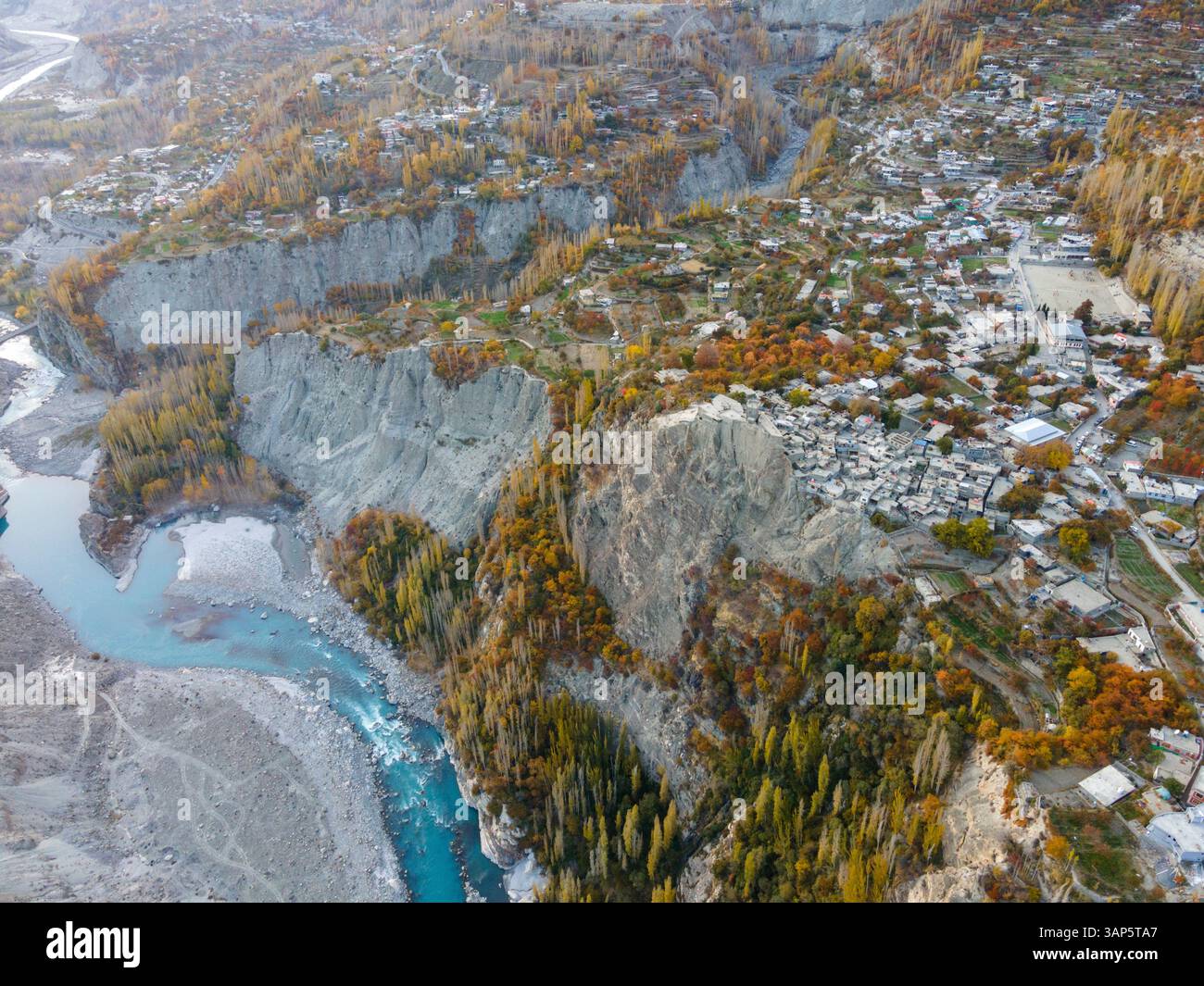 Aerial view of serene valley with river, village, and cliff in Hunza ...