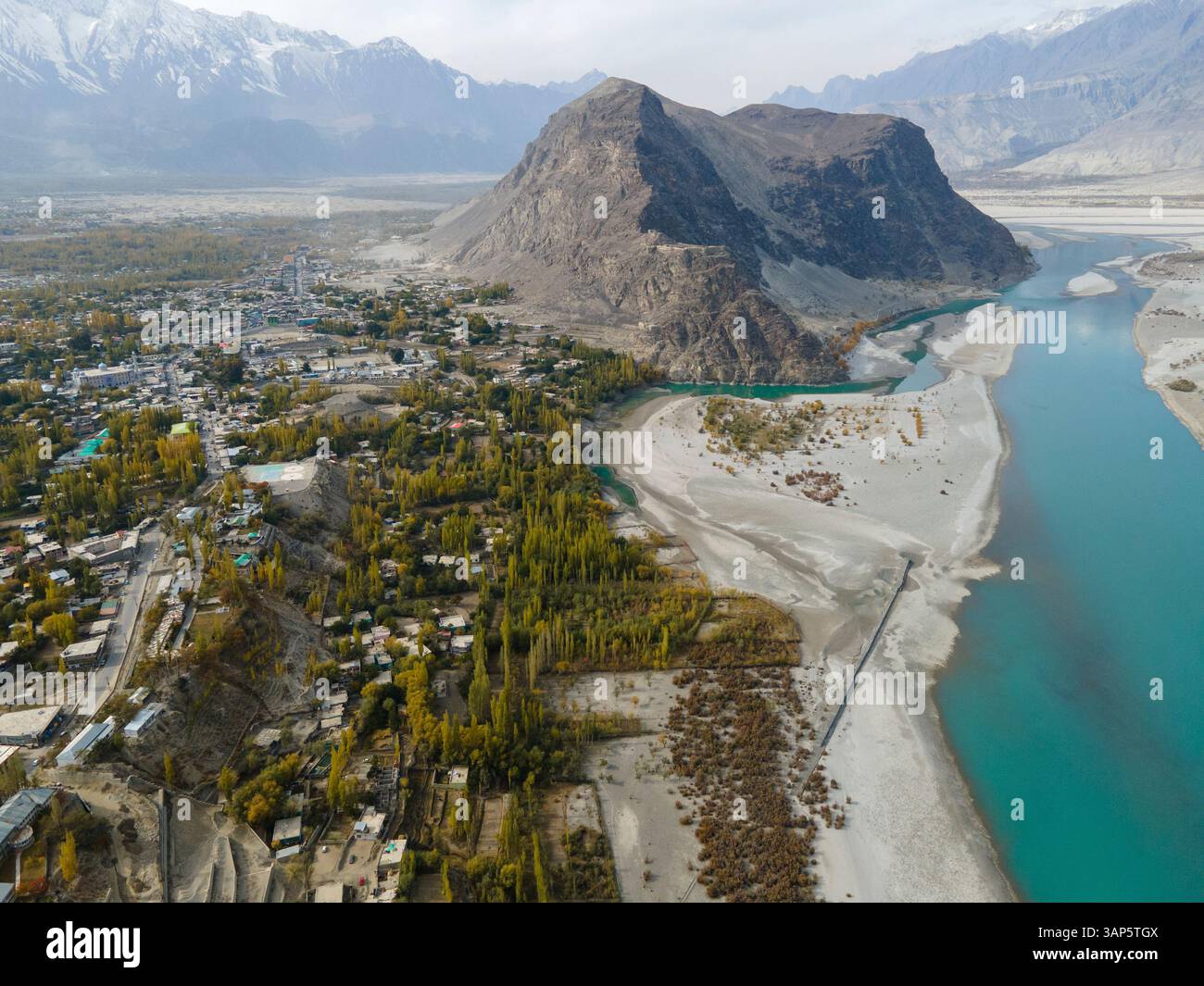 Aerial view of remote village by Indus River with majestic mountains ...