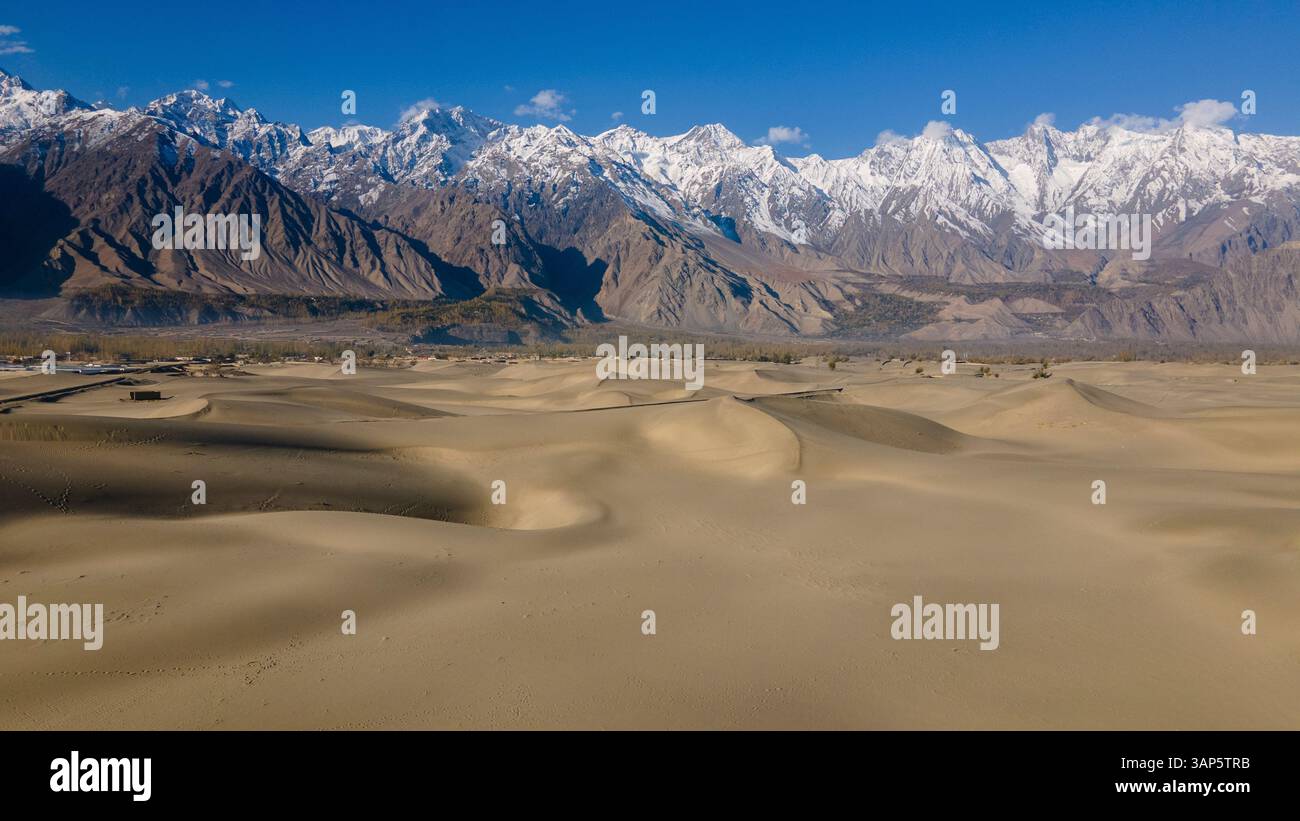 Aerial view of majestic snow-capped mountains and vast desert with sand ...