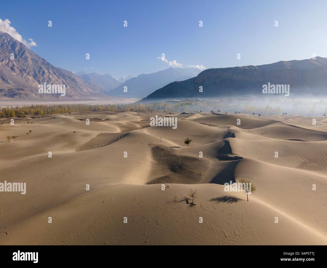 Aerial view of Katpana Desert with sand dunes, mountains, and vast sky ...