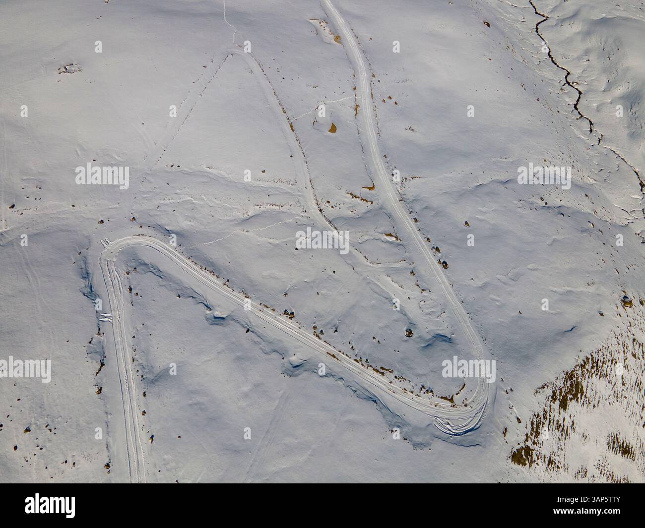 Aerial view of snow-covered road winding through majestic mountains ...