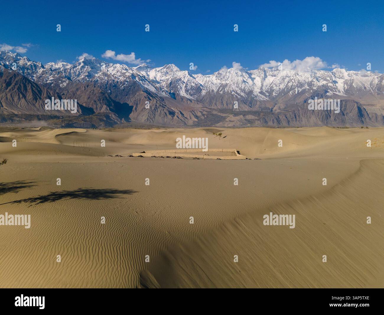 Aerial view of Katpana Desert with snow capped peaks and sand dunes ...