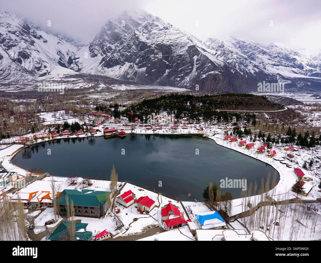 Aerial view of snowy mountains, serene lake, and picturesque village ...