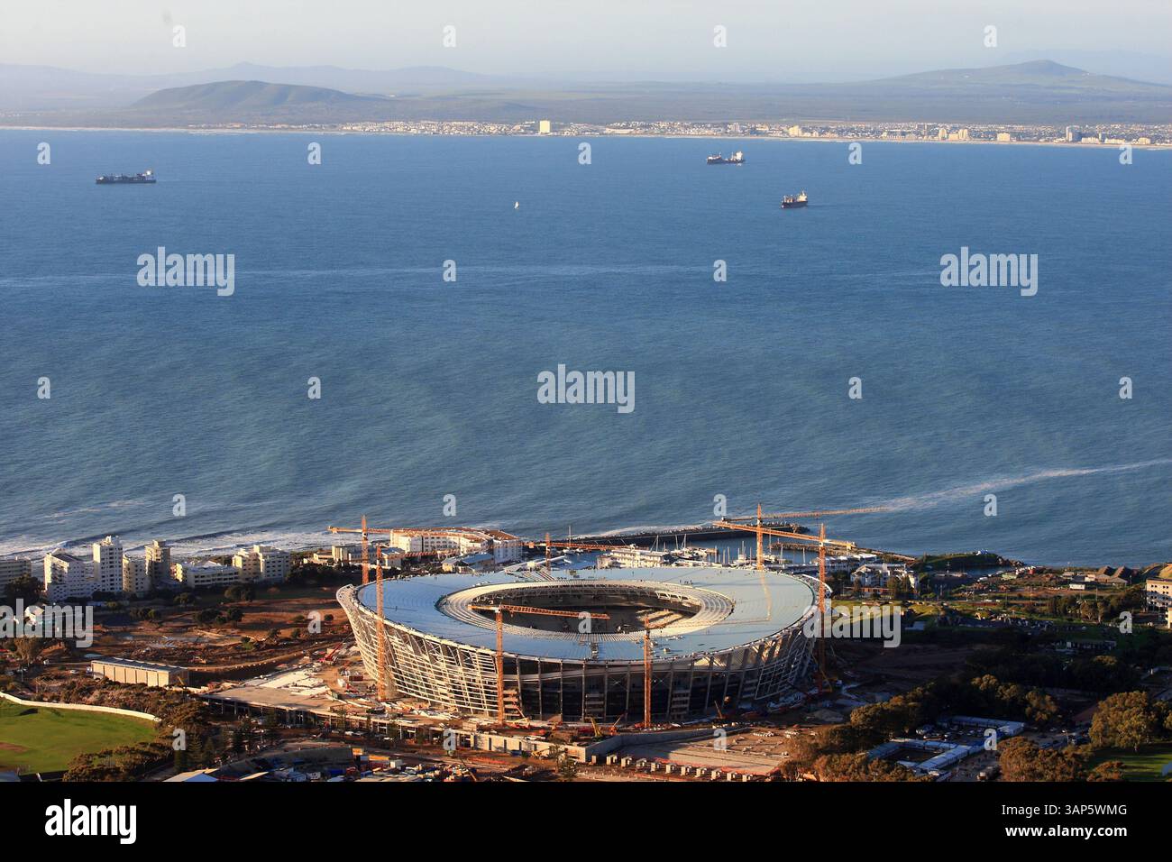 Aerial view of Cape Town Stadium by the ocean with city and mountains ...