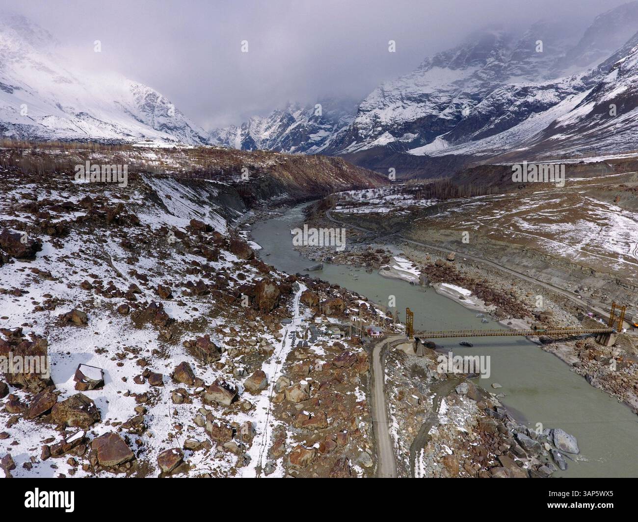 Aerial view of snow-covered mountain peaks and icy river in remote ...
