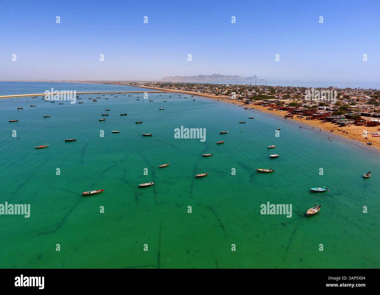 Aerial view of tranquil village by turquoise ocean with fishing boats ...