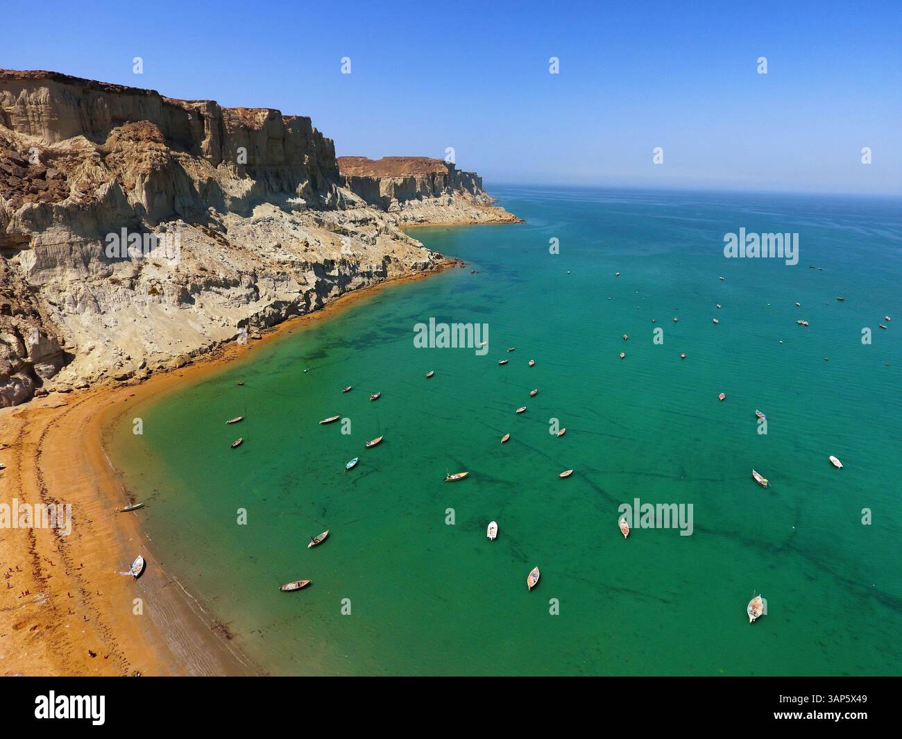 Aerial view of boats on turquoise water with cliffs and sandy beach ...