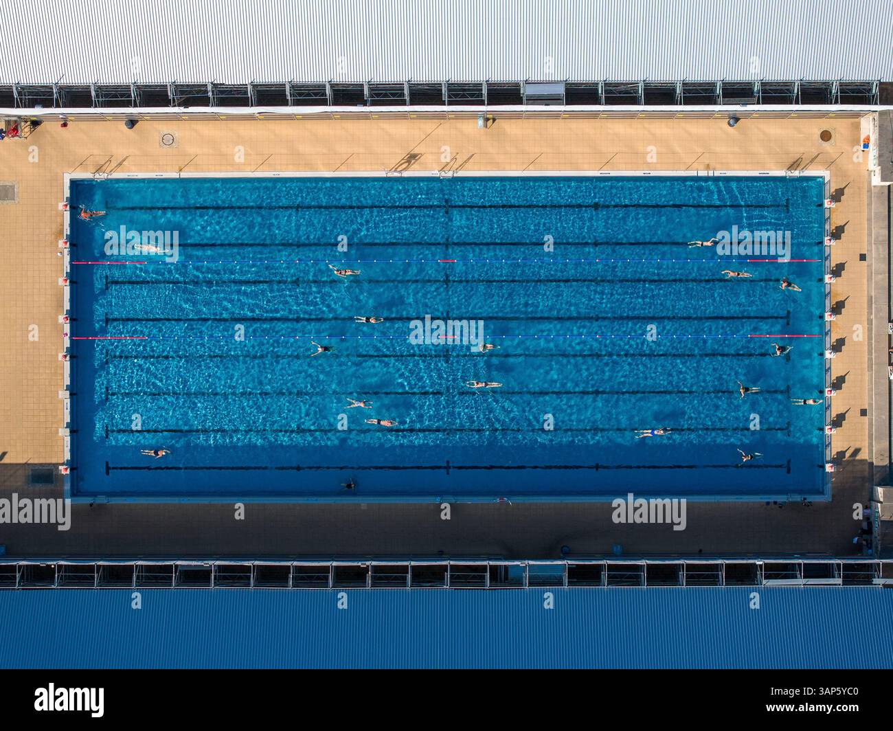Aerial view of people swimming in public pools surrounded by blue water ...