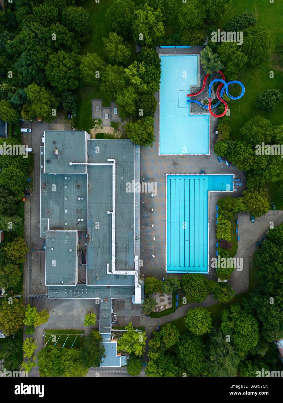 Aerial view of public pools with water slides surrounded by greenery ...