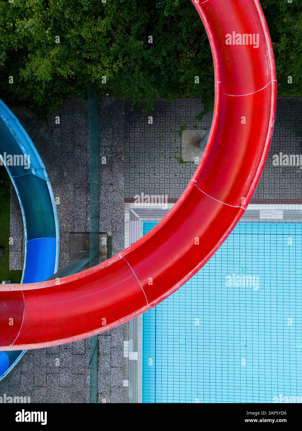 Aerial view of public pools with red and blue waterslides surrounded by ...