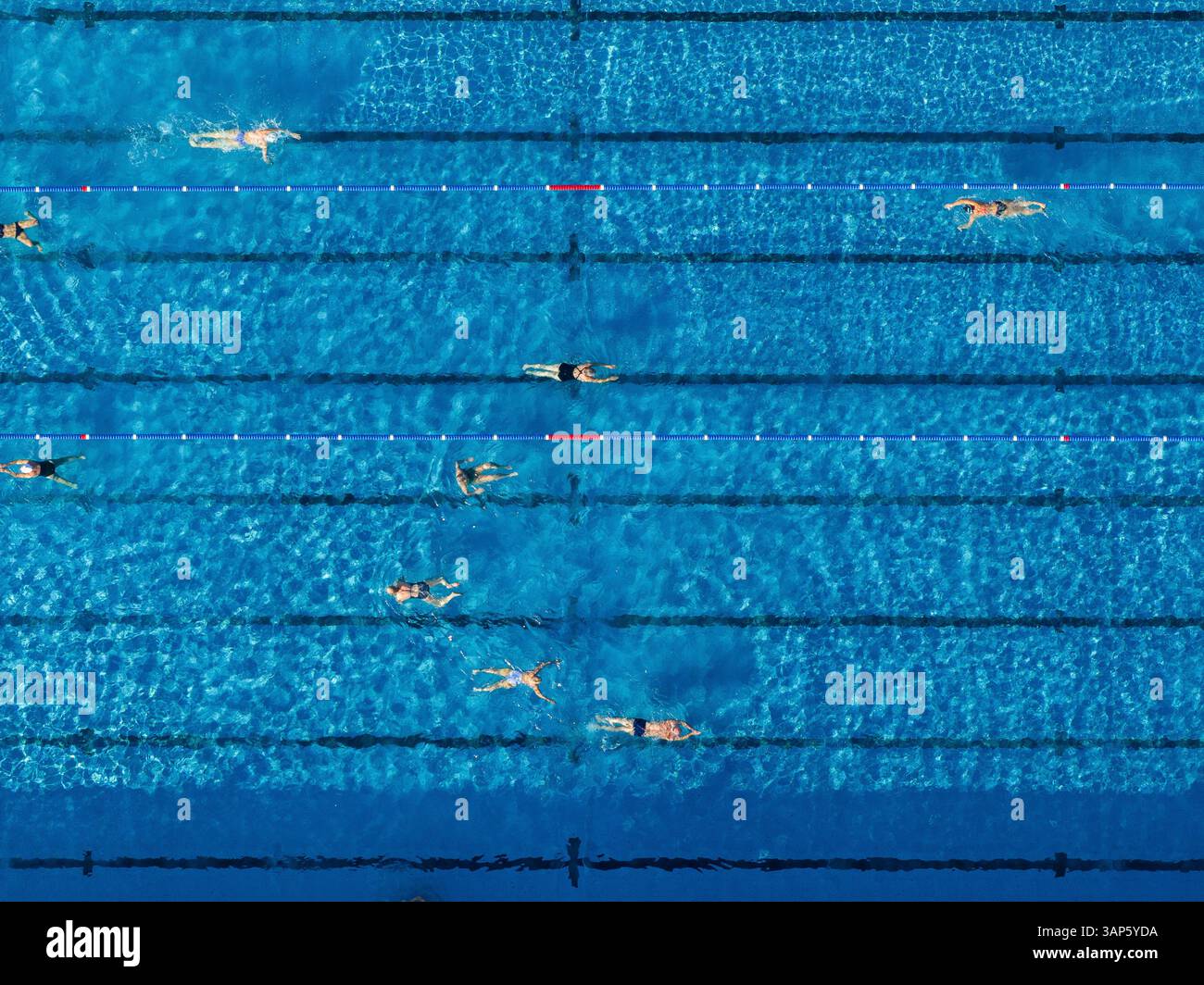 Aerial view of public pools with people swimming in vibrant blue water ...