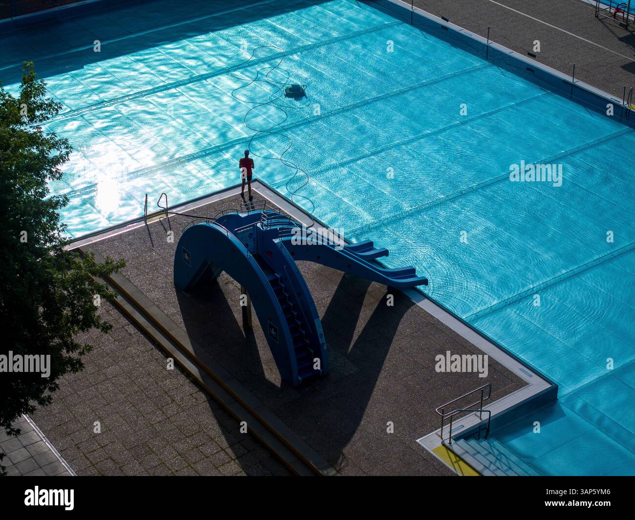 Aerial view of a sparkling public swimming pool with a slide and trees ...