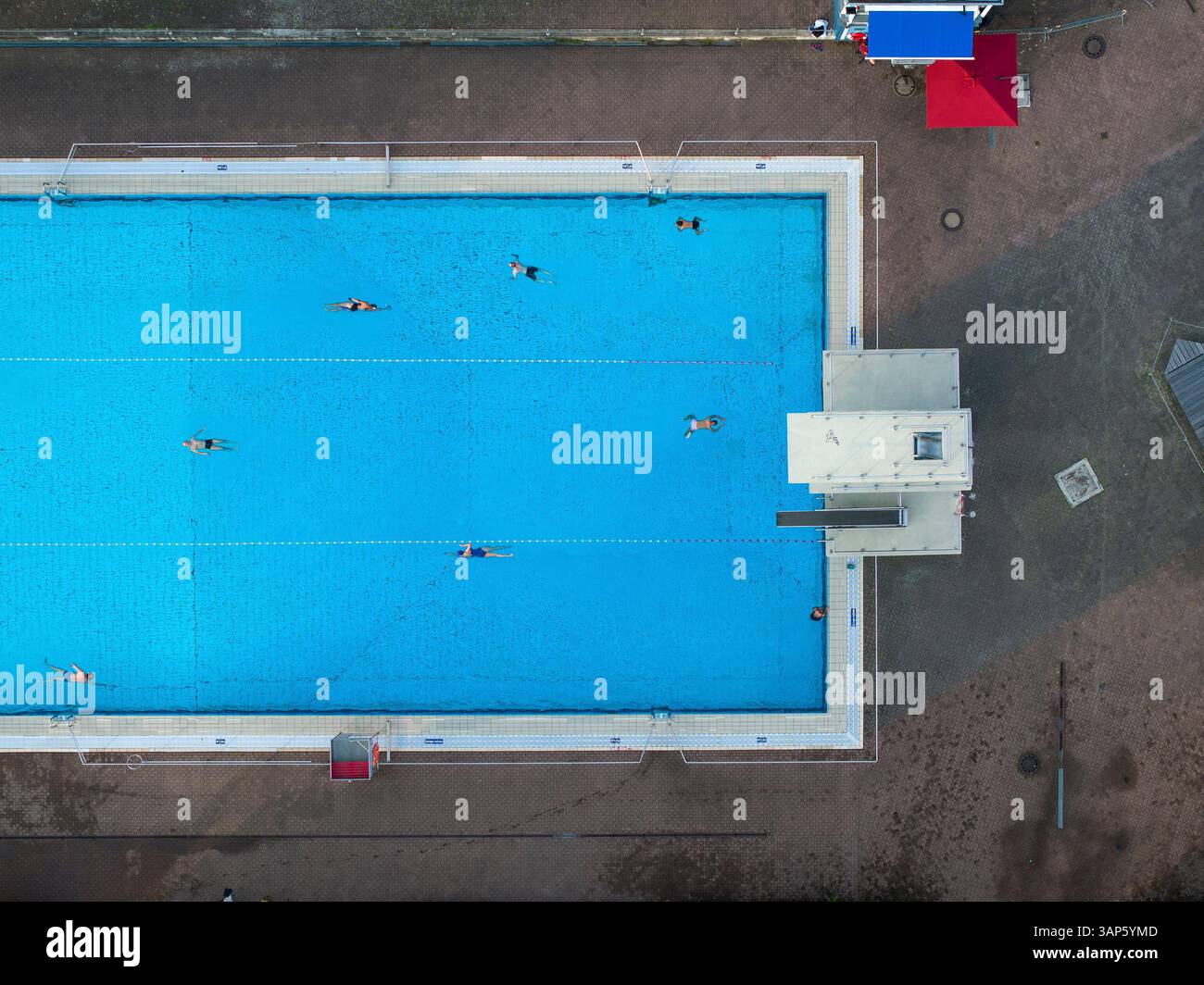 Aerial view of vibrant public pool with swimmers and diving board ...