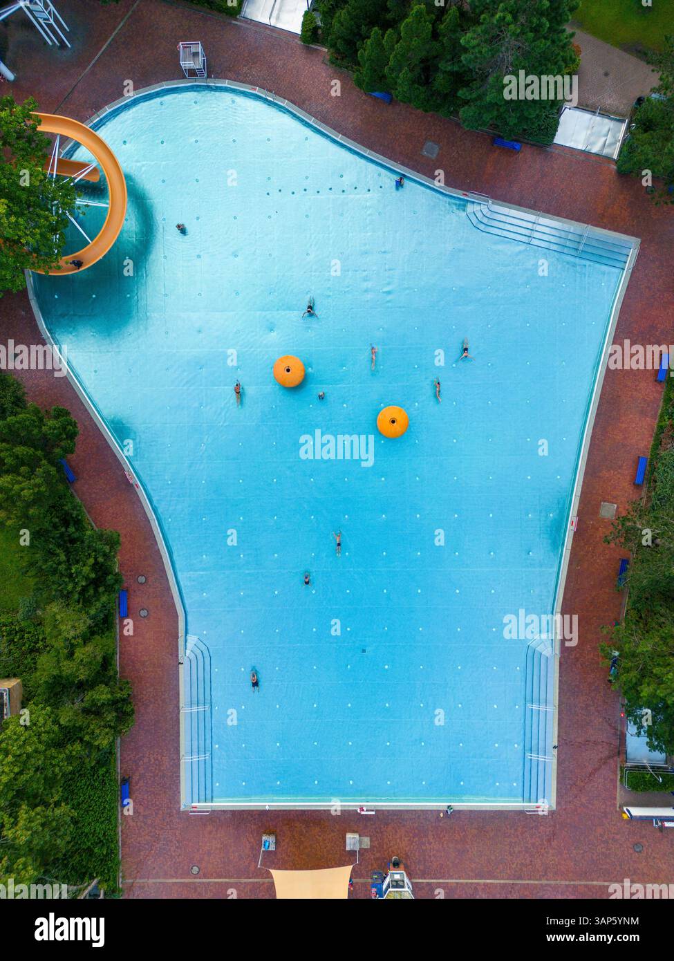 Aerial view of public pools with people swimming surrounded by trees ...