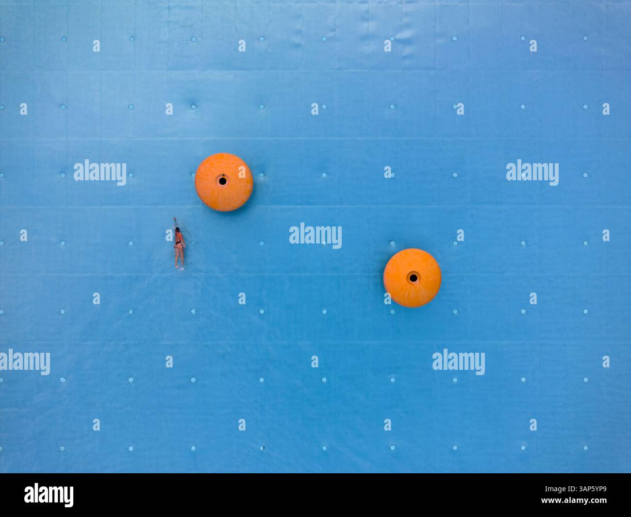 Aerial view of public pools with swimmers and colorful orange floats ...