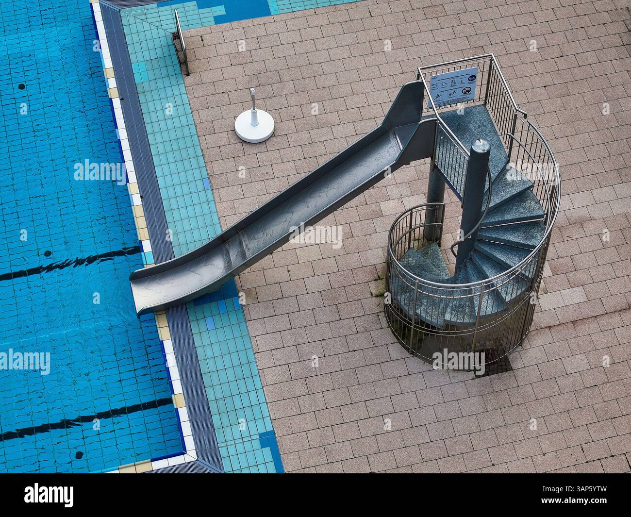 Aerial view of an empty public pool with a spiral staircase and slide ...