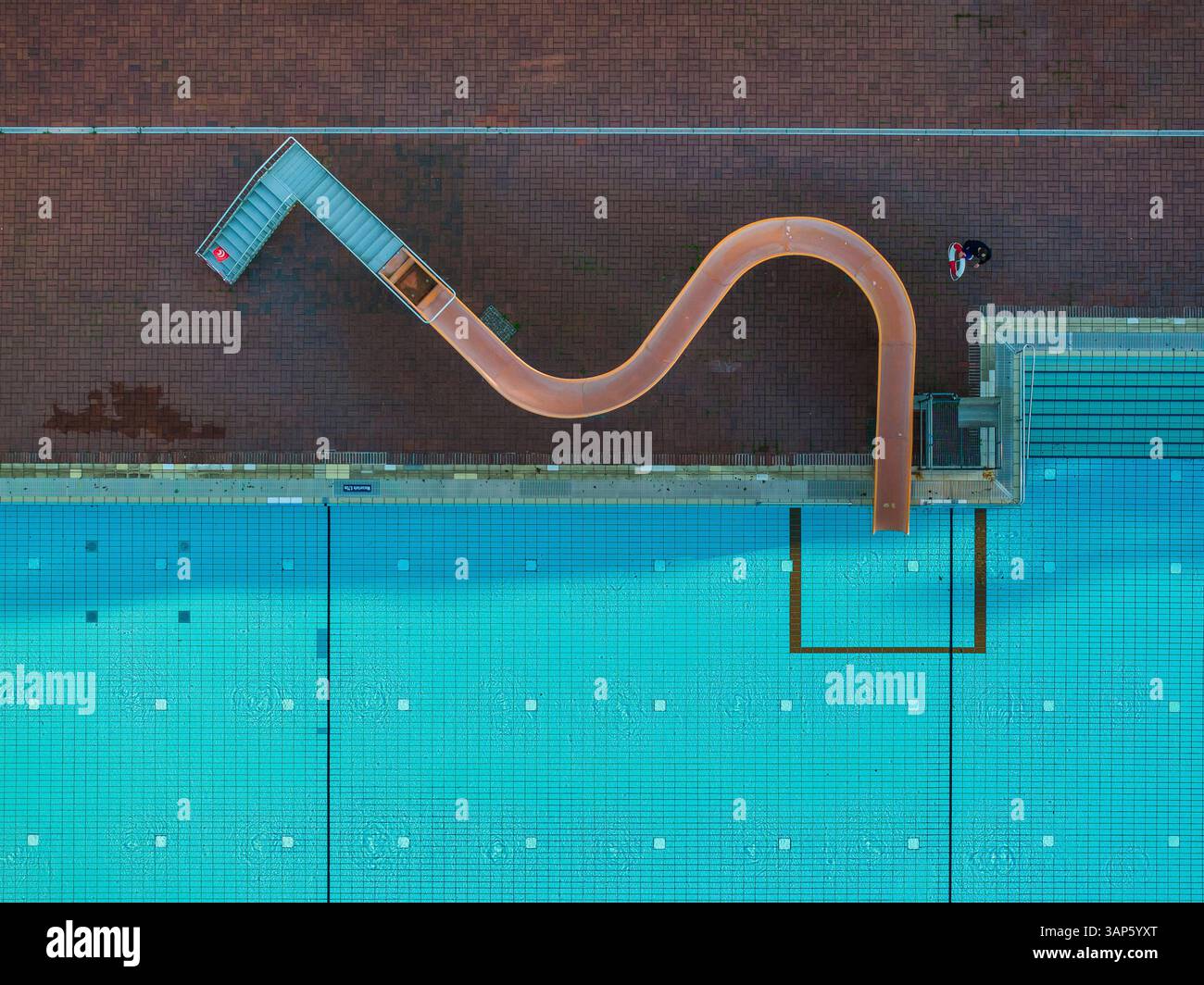 Aerial view of a beautiful public pool with turquoise water and a slide ...