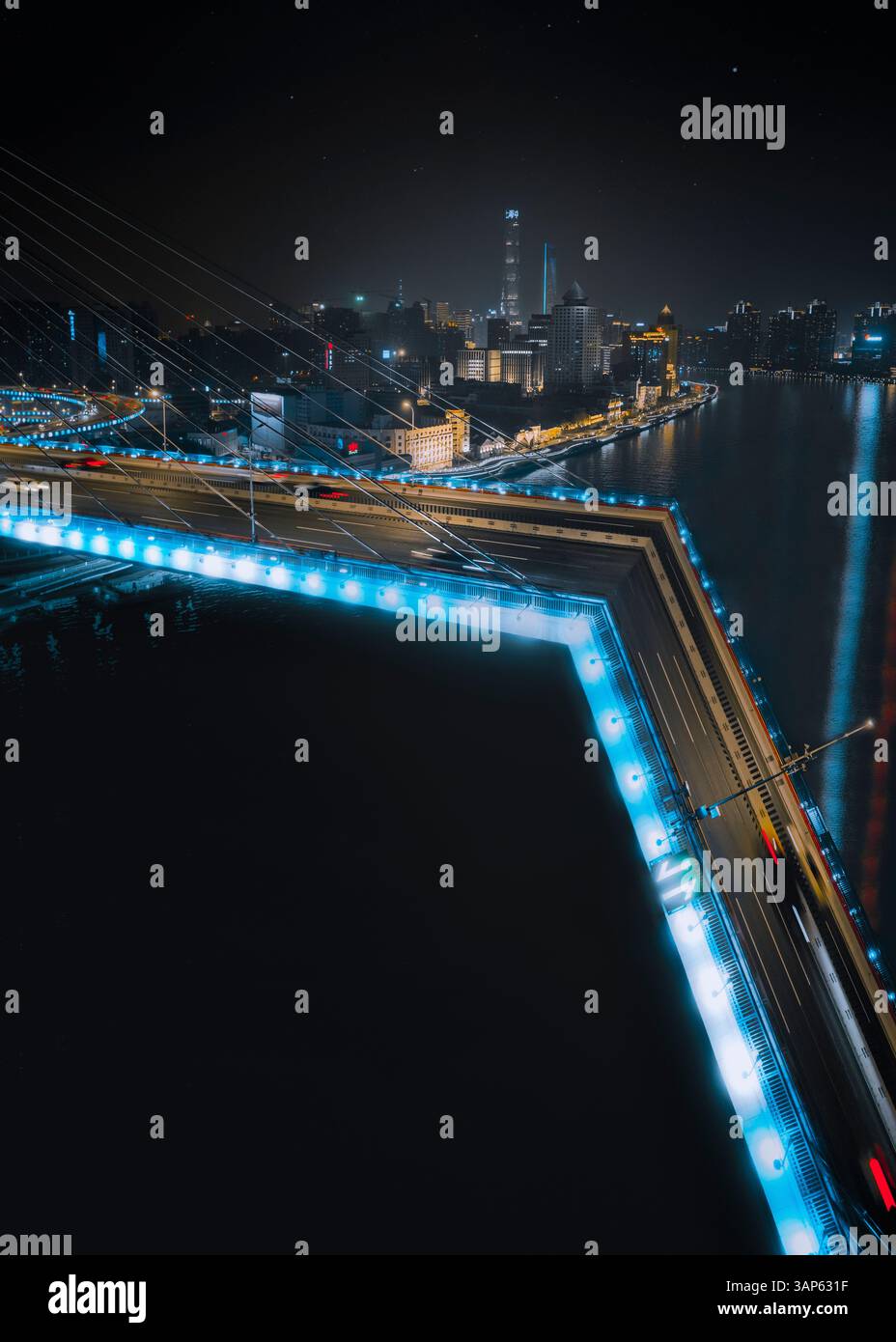 Aerial view of an illuminated suspended bridge at night with Shanghai ...