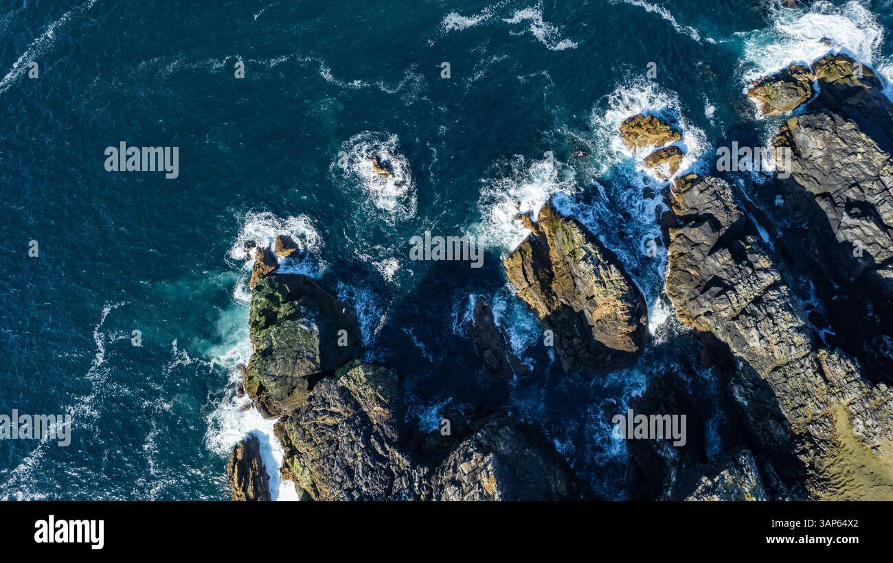 Aerial view of rugged cliffs and crashing waves along the coastline ...