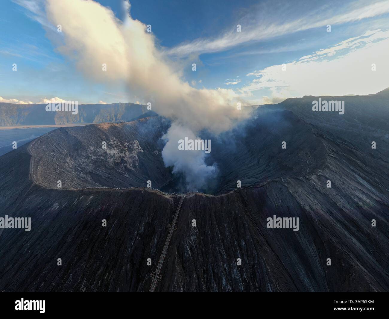 Aerial view of majestic Bromo volcano with smoke rising from its crater ...