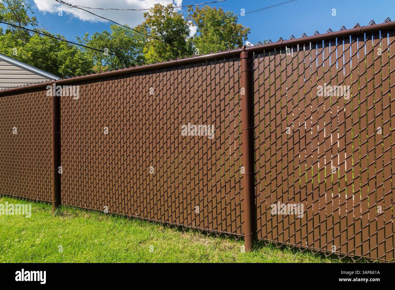 Brown chain-link fence with privacy slats in residential backyard ...