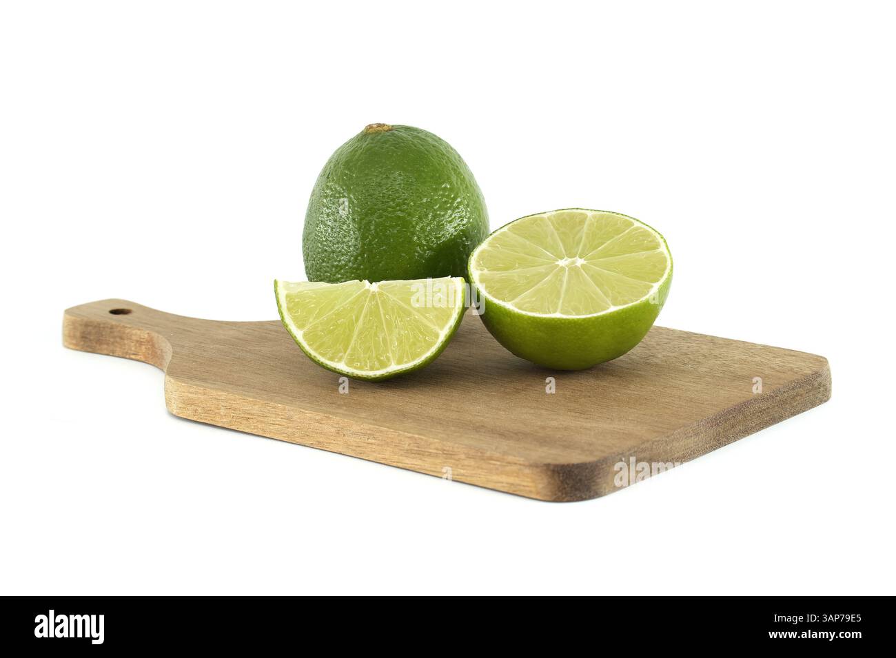 One whole lime, one half and one wedge are laying on a small wooden ...
