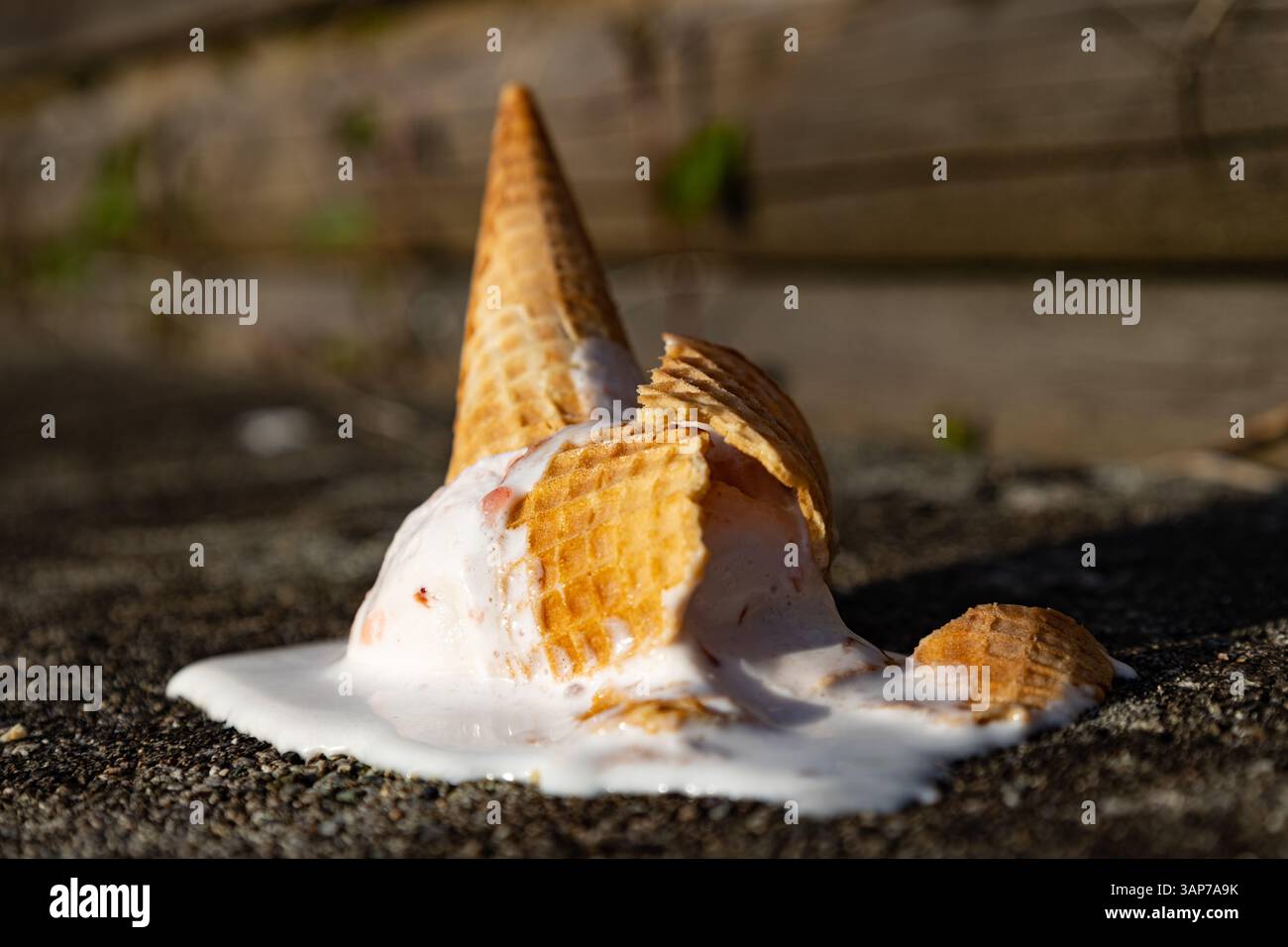 A half eaten ice cream cone with a white liquid dripping from it. The ...