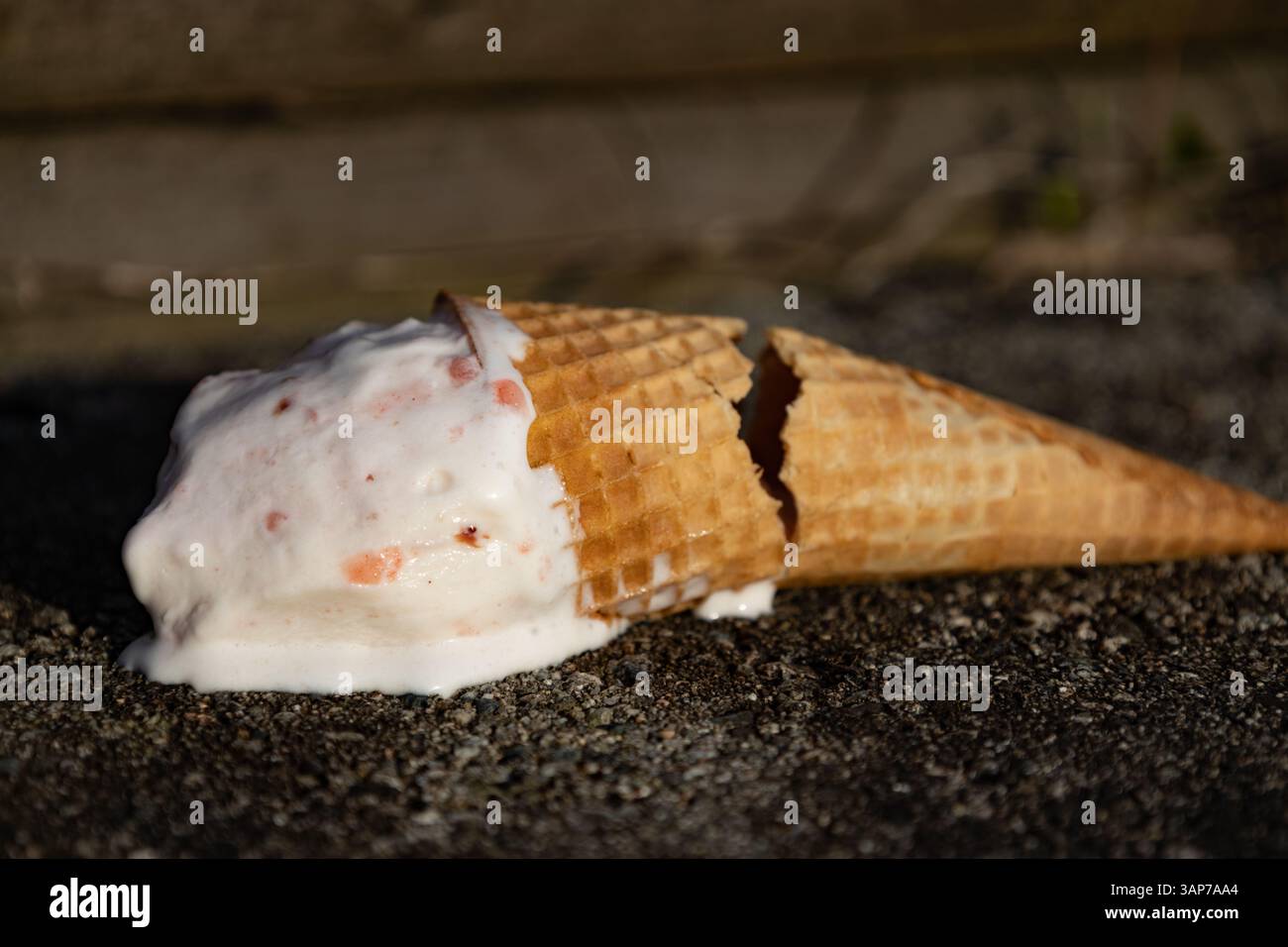 A half eaten ice cream cone with a white liquid dripping from it. The ...
