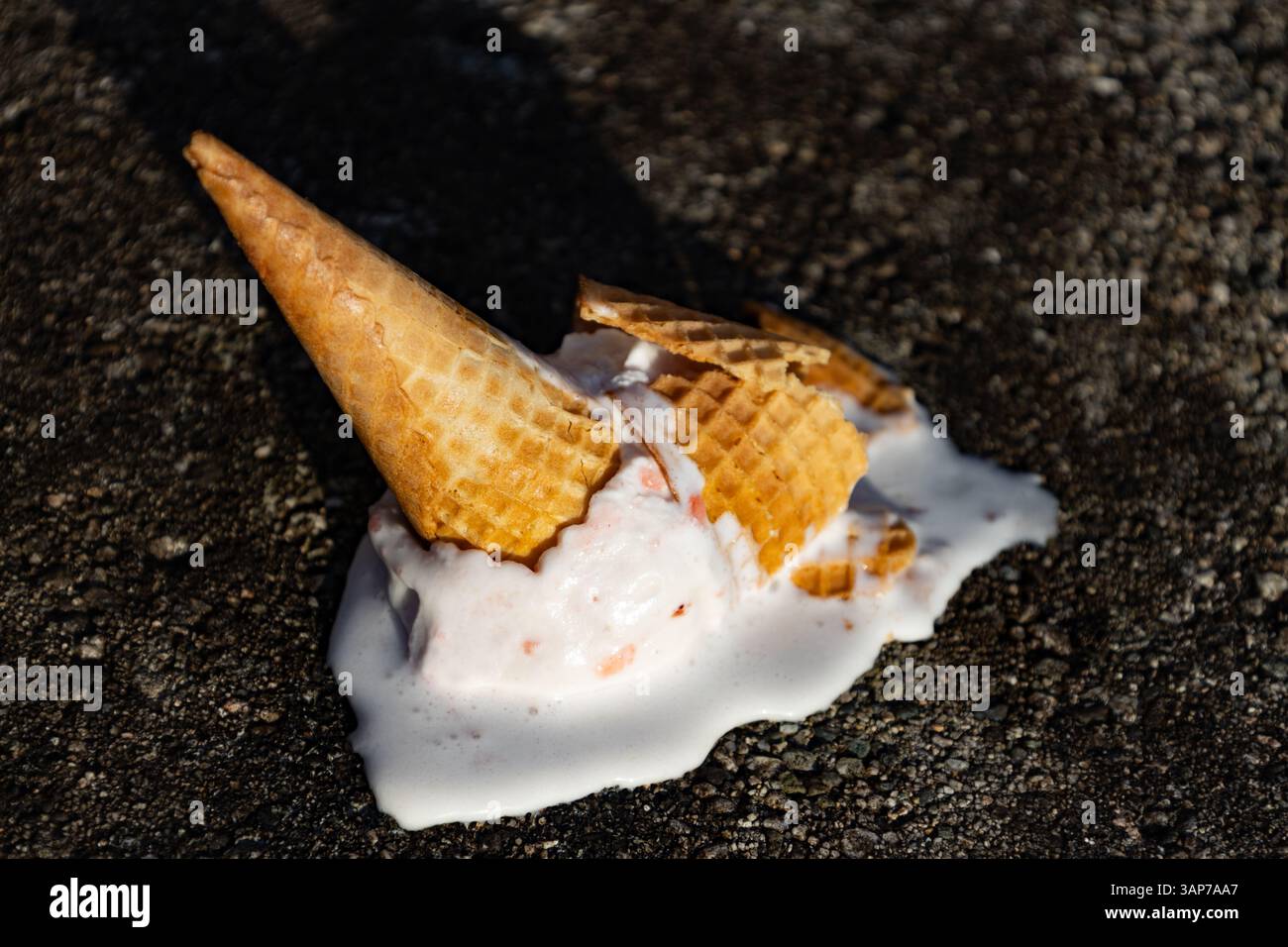 A half eaten ice cream cone with a white liquid dripping from it. The ...