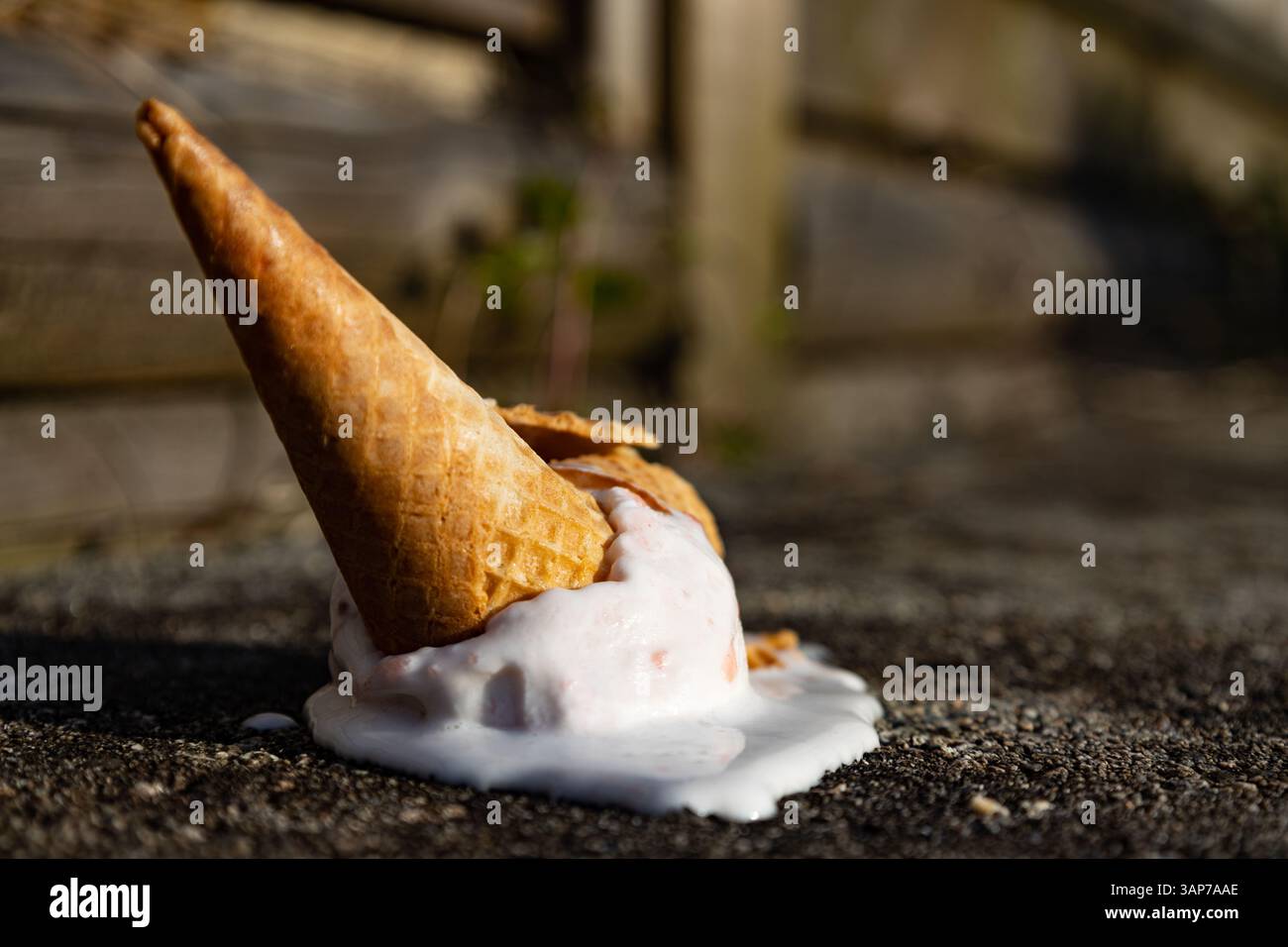 A half eaten ice cream cone with a white liquid dripping from it. The ...