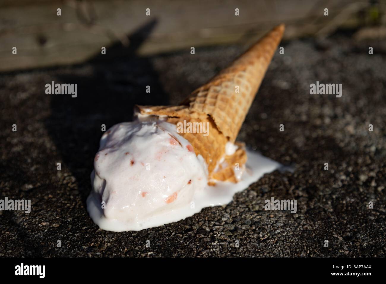 A half eaten ice cream cone with a white liquid dripping from it. The ...