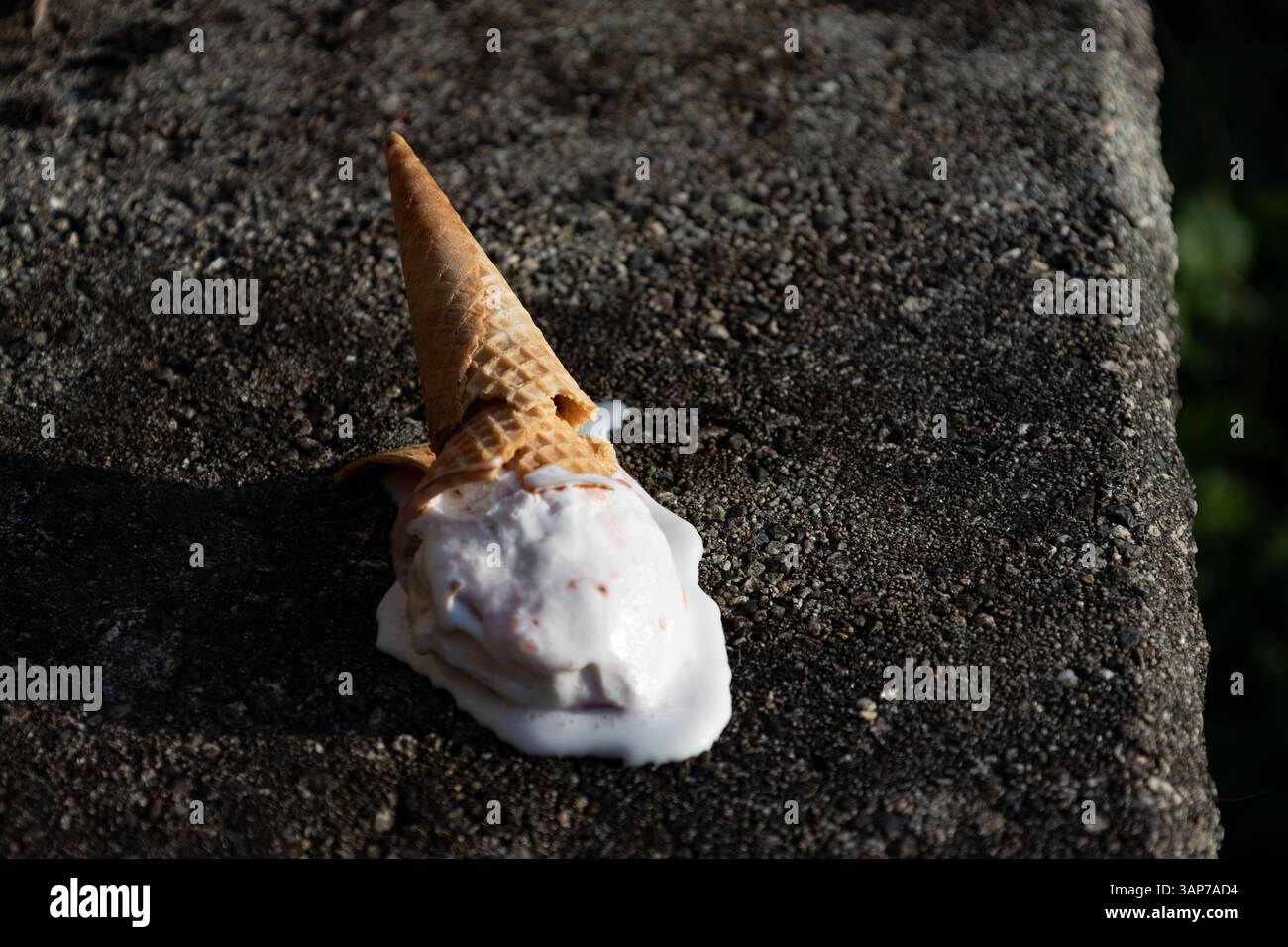 A half eaten ice cream cone with a white liquid dripping from it. The ...