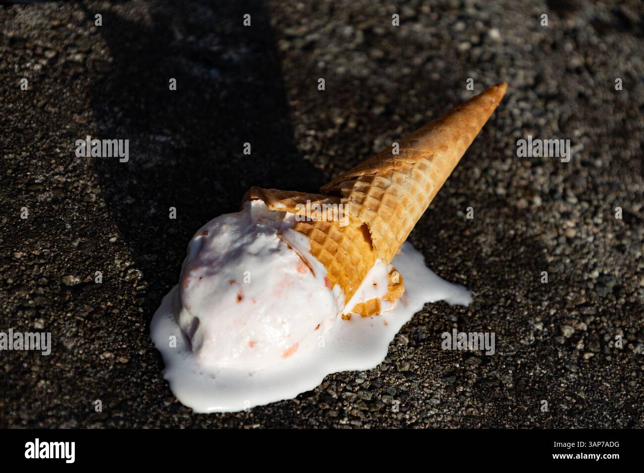 A half eaten ice cream cone with a white liquid dripping from it. The ...