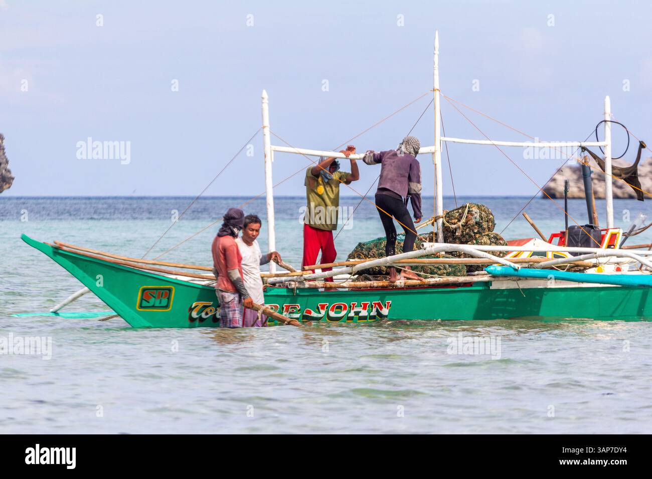 Filipino fishermen transporting harvested scallop shells from boat to ...