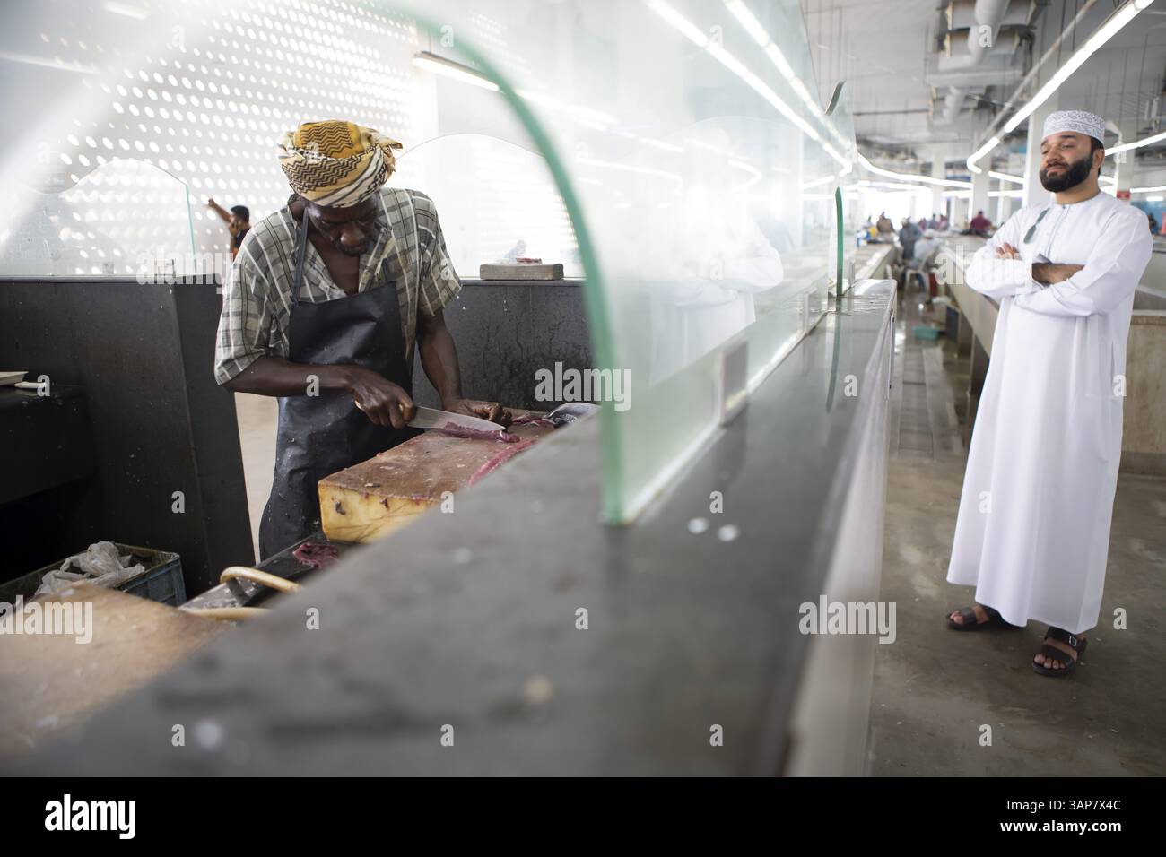 Omani man filleting a fish in Muttrah fish market, Omani man in ...