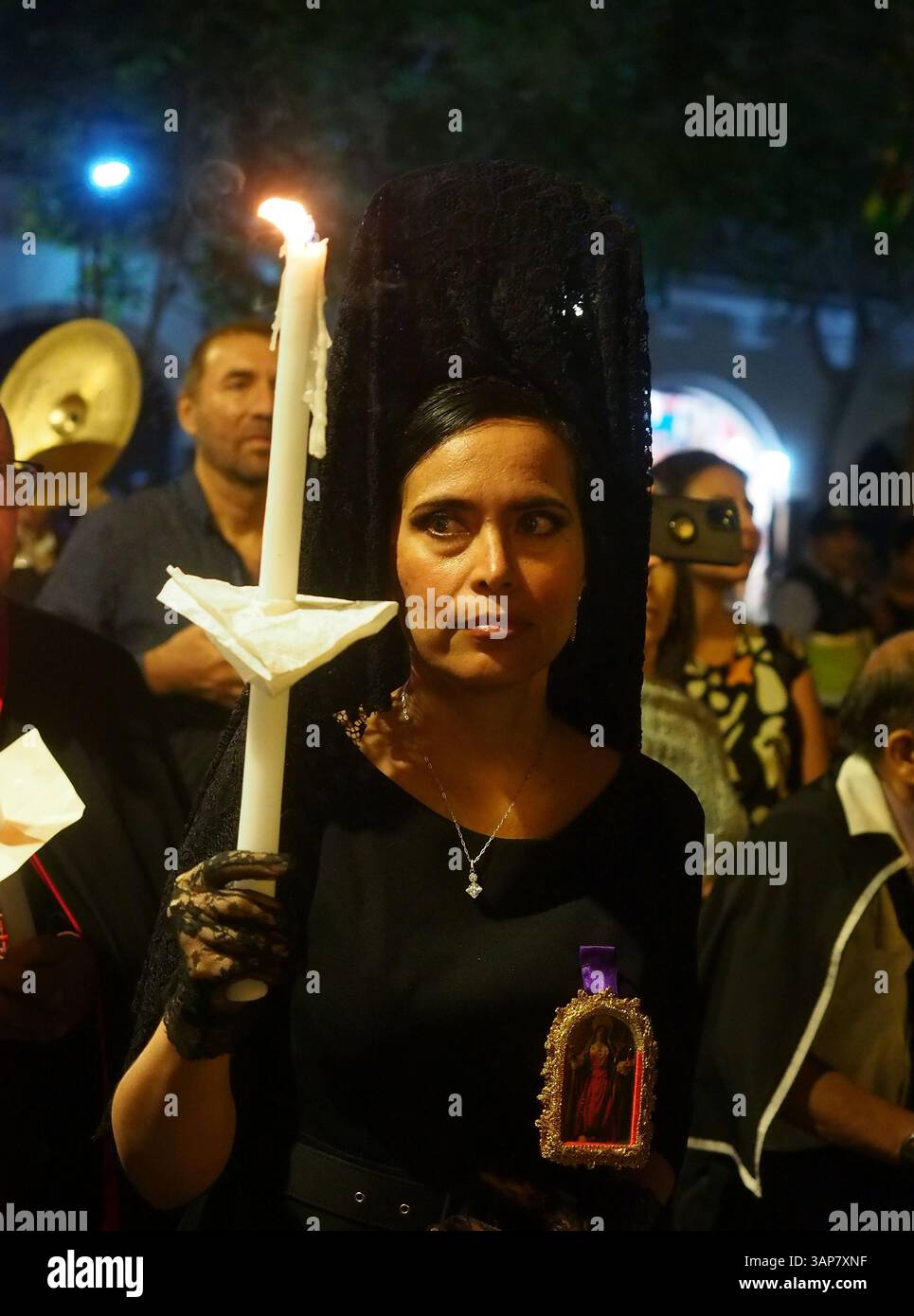 Devotee with a candle wearing habit and mantilla participating in a ...