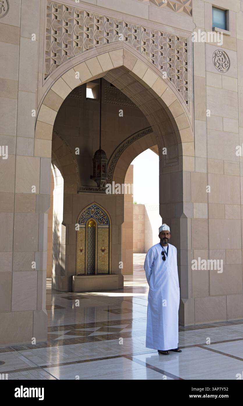 Omani man in dishdasha at an archway in the Sultan Qabus Grand Mosque ...