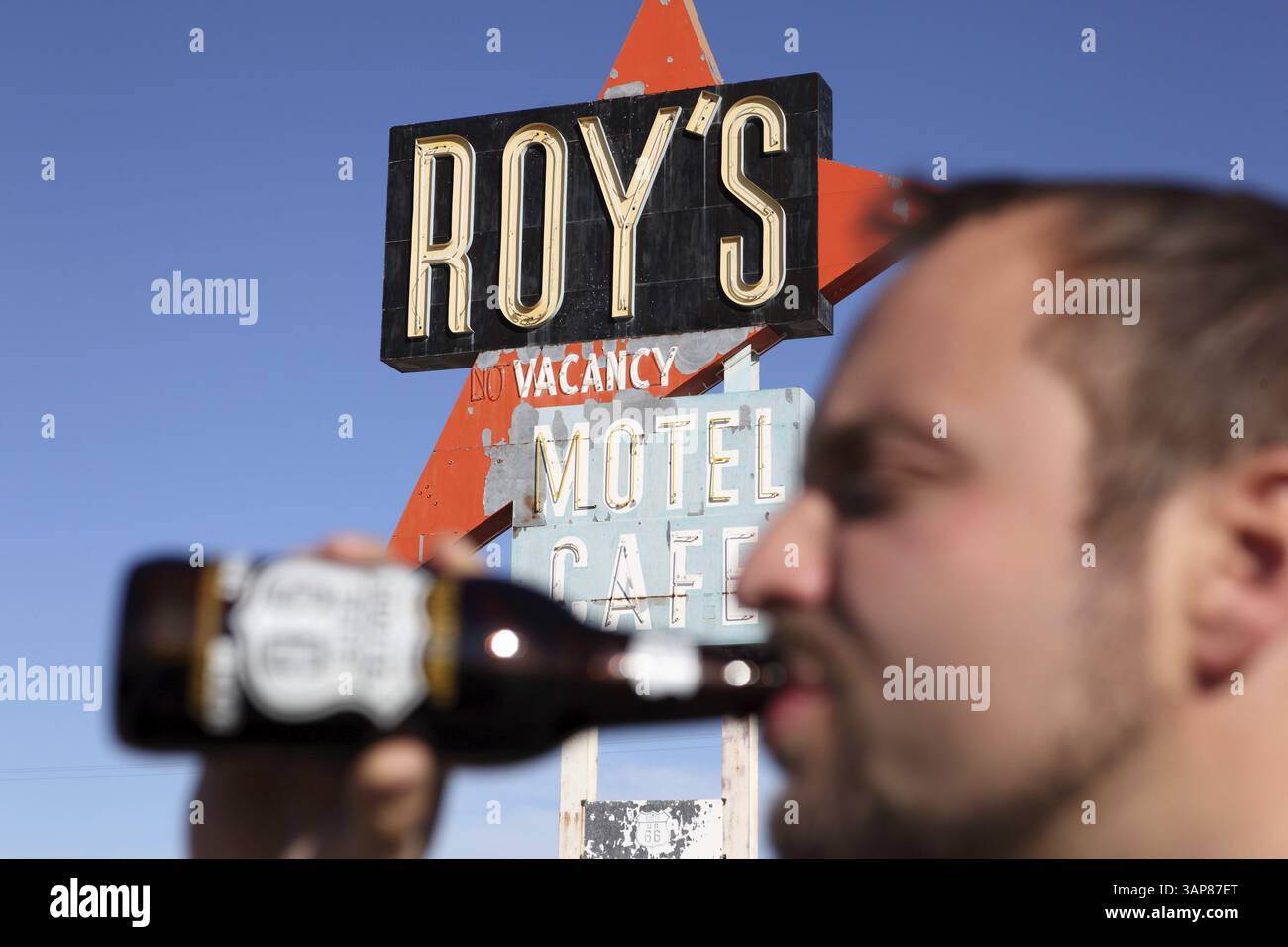 A man drinks a root beer in front of Roy' Motel sign on Route 66 in ...