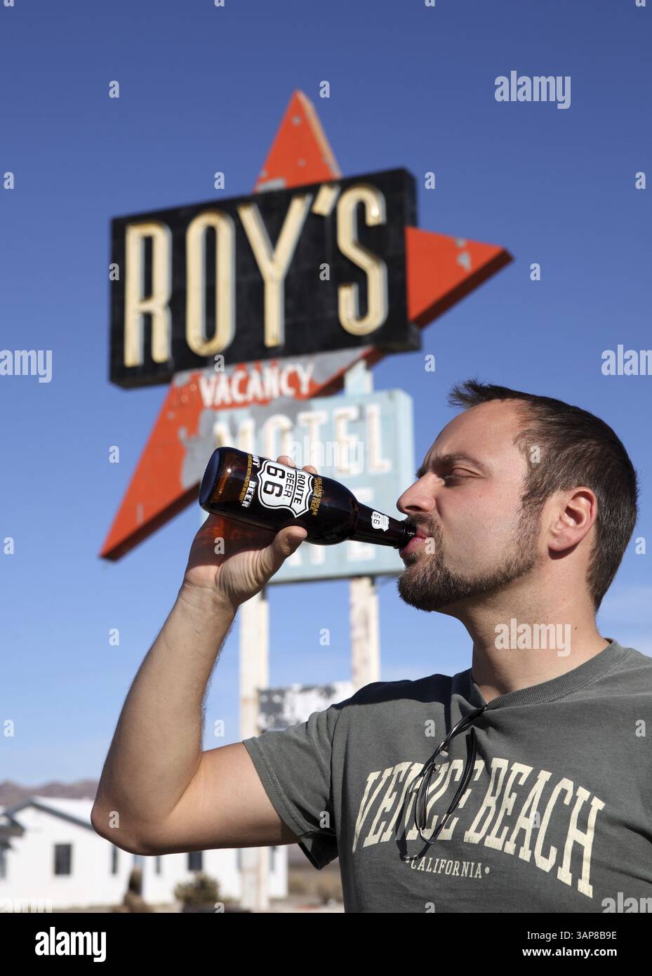 A man drinks a root beer in front of Roy' Motel sign on Route 66 in ...