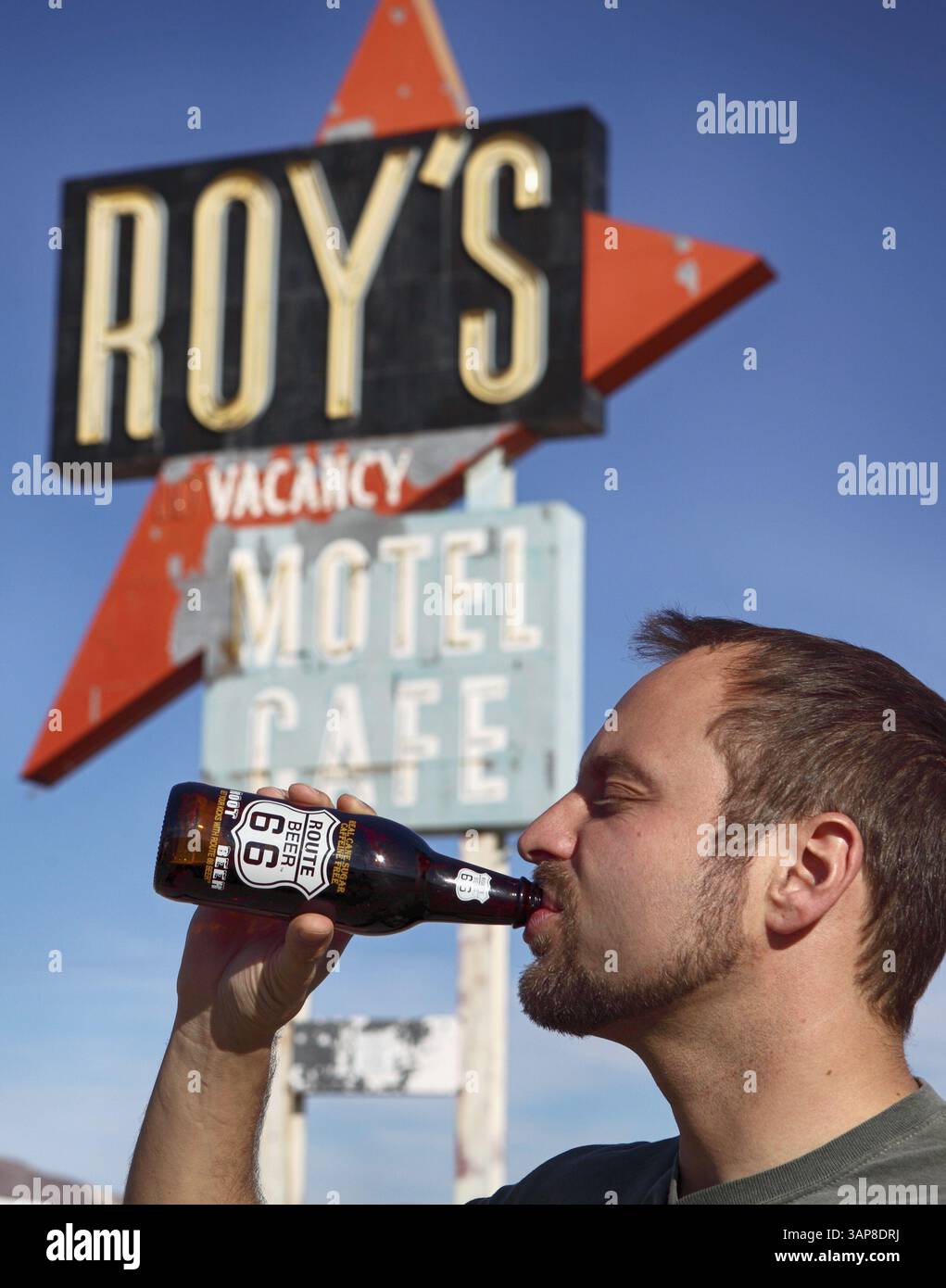 Man drinking a root beer in front of Roy's Motel sign on Route 66 in ...